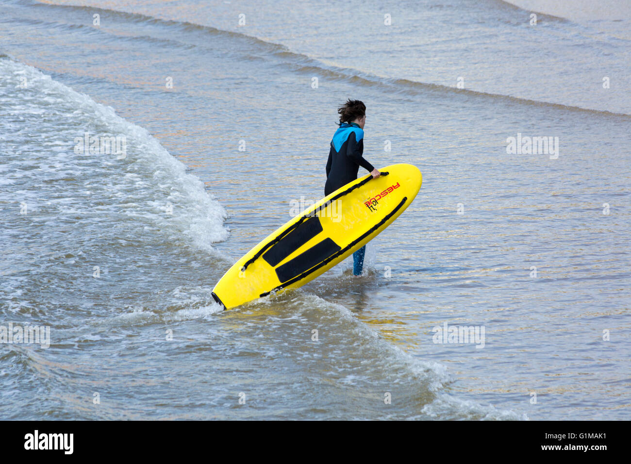 RNLI lifeguard carrying rescue life sled surf board from the sea at ...
