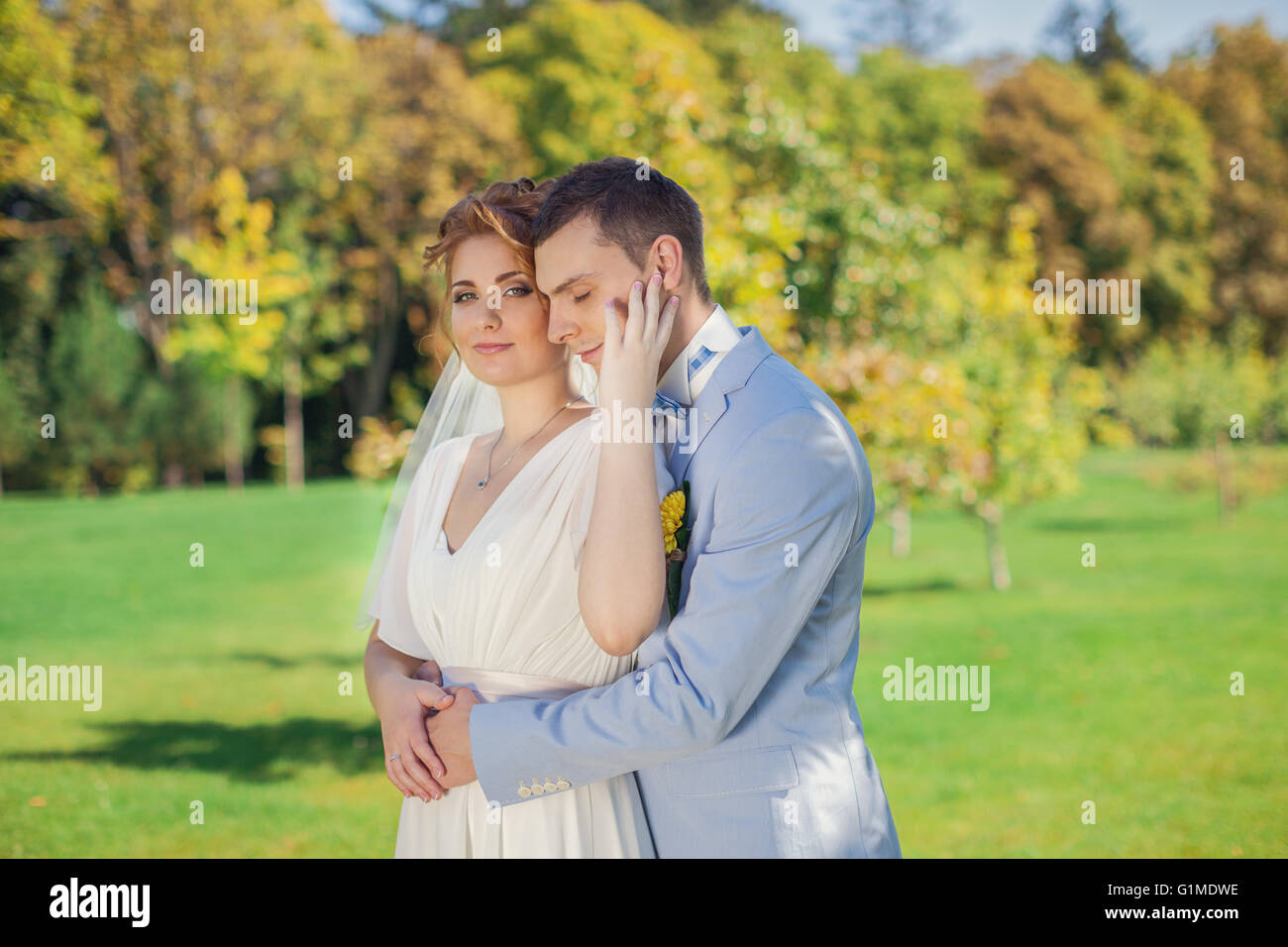 The groom gently embraces the bride Stock Photo - Alamy