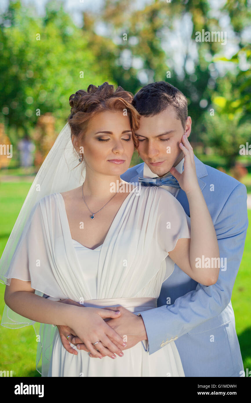 The groom gently embraces the bride Stock Photo - Alamy
