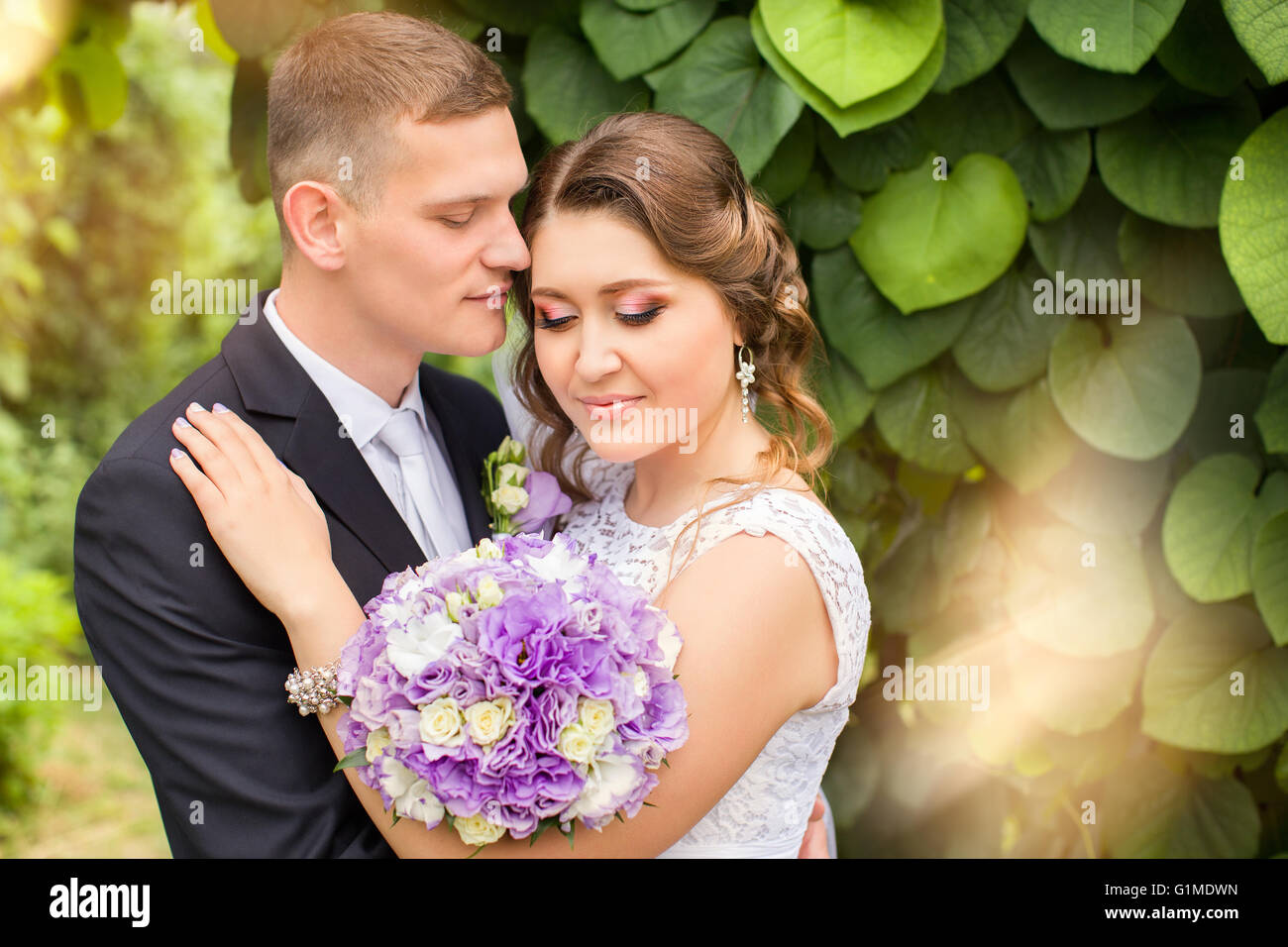 The groom gently embraces the bride Stock Photo - Alamy
