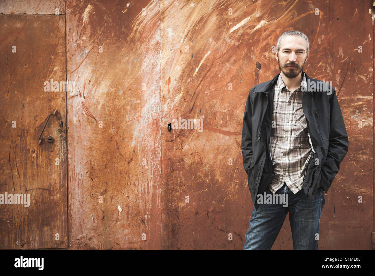 Outdoor portrait of young bearded Asian man in casual clothes on rusted ...