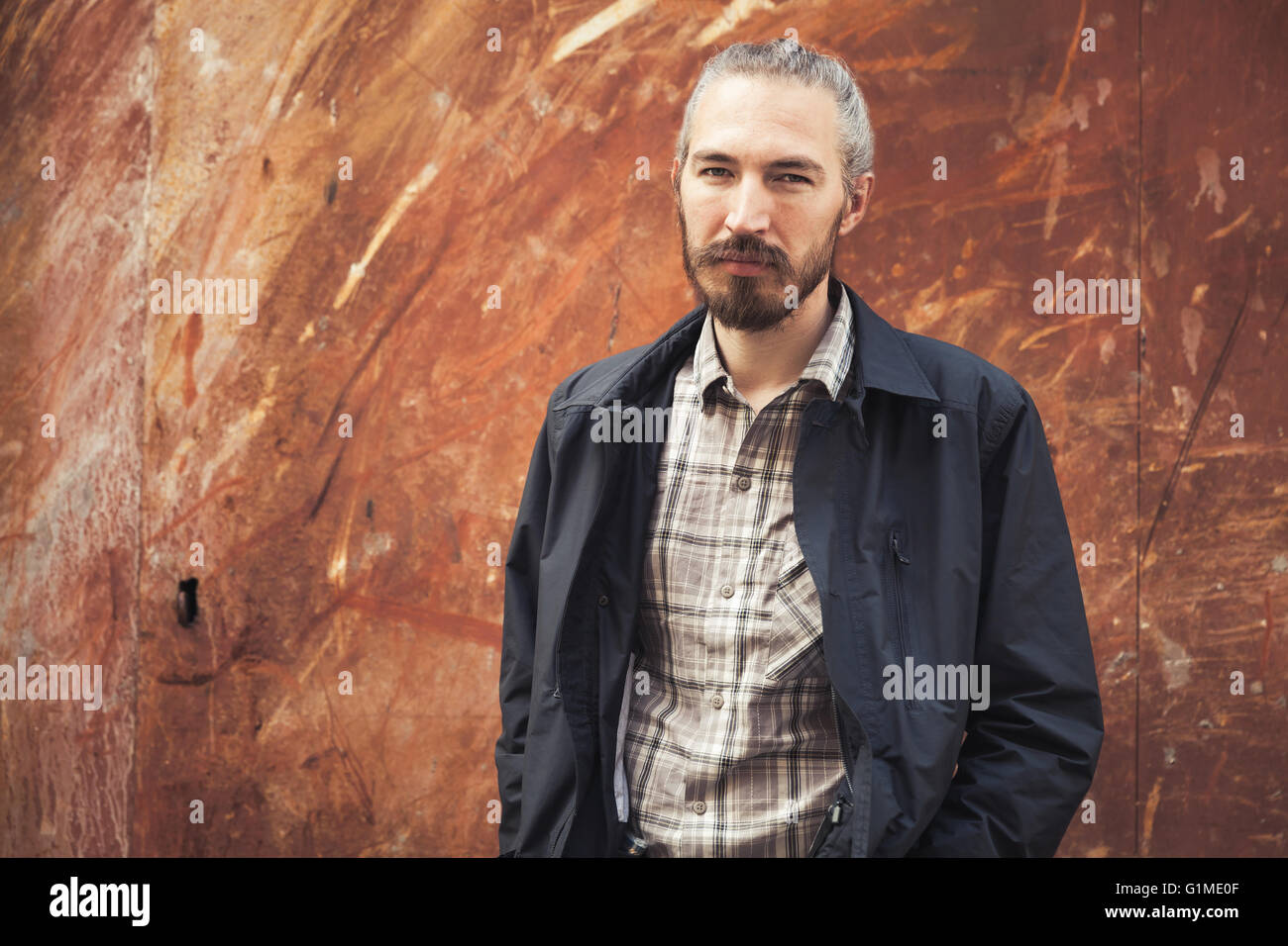 Outdoor portrait of bearded Asian man in casual clothes on rusted urban ...