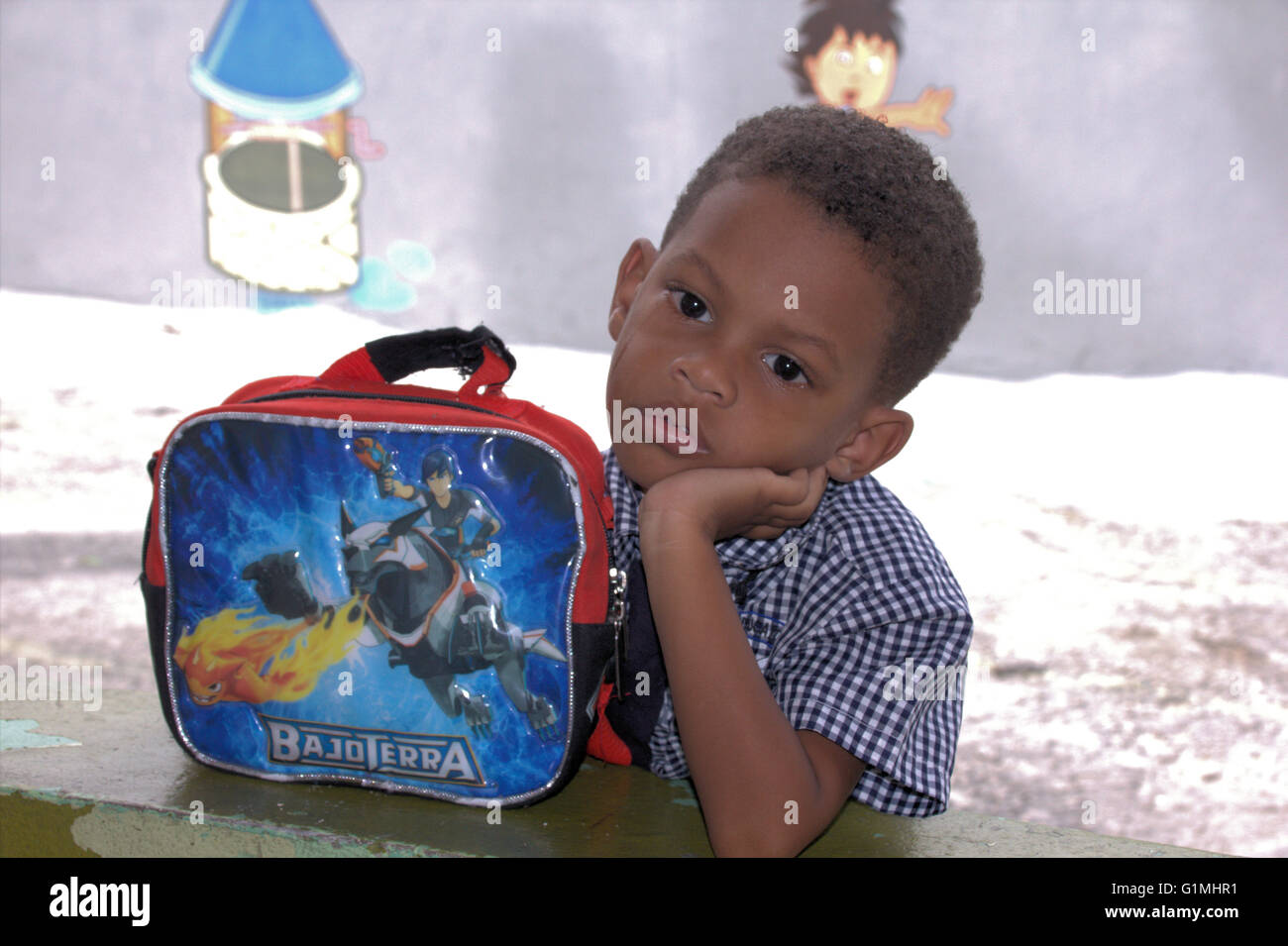 A very sad young boy sits with his lunch box at snack time Stock Photo ...