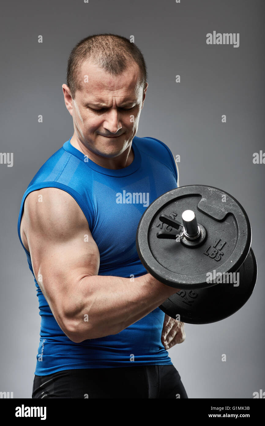 Man doing biceps curl with dumbbell on gray background Stock Photo - Alamy