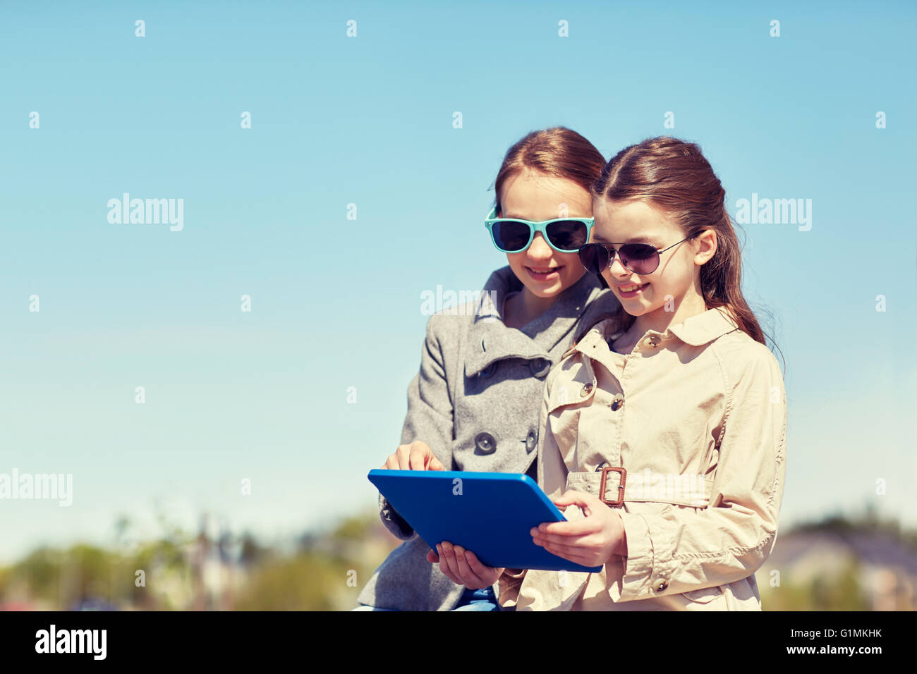 happy girls with tablet pc computer outdoors Stock Photo - Alamy