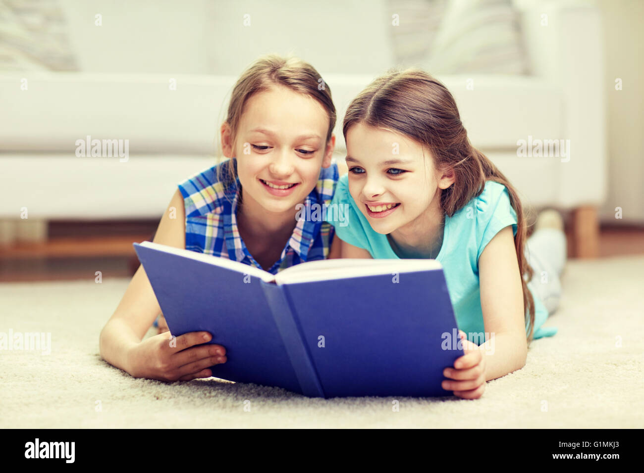 two happy girls reading book at home Stock Photo - Alamy
