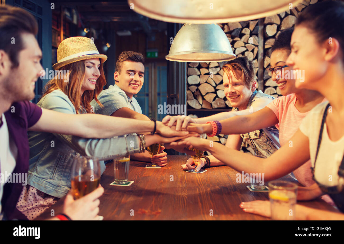 happy friends with drinks and hands on top at bar Stock Photo - Alamy