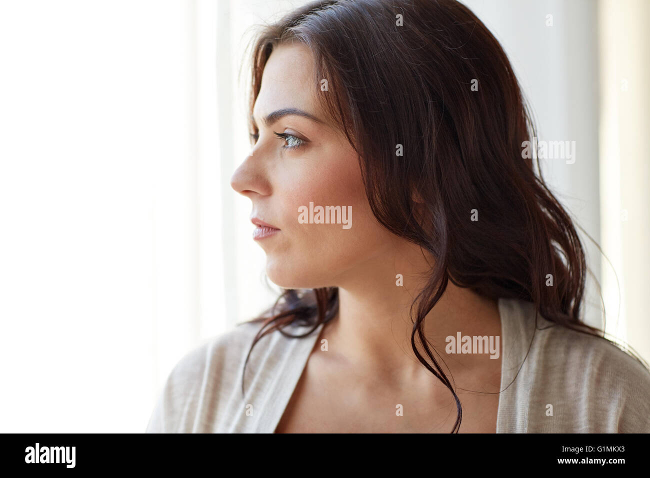 young woman looking through window at home Stock Photo - Alamy