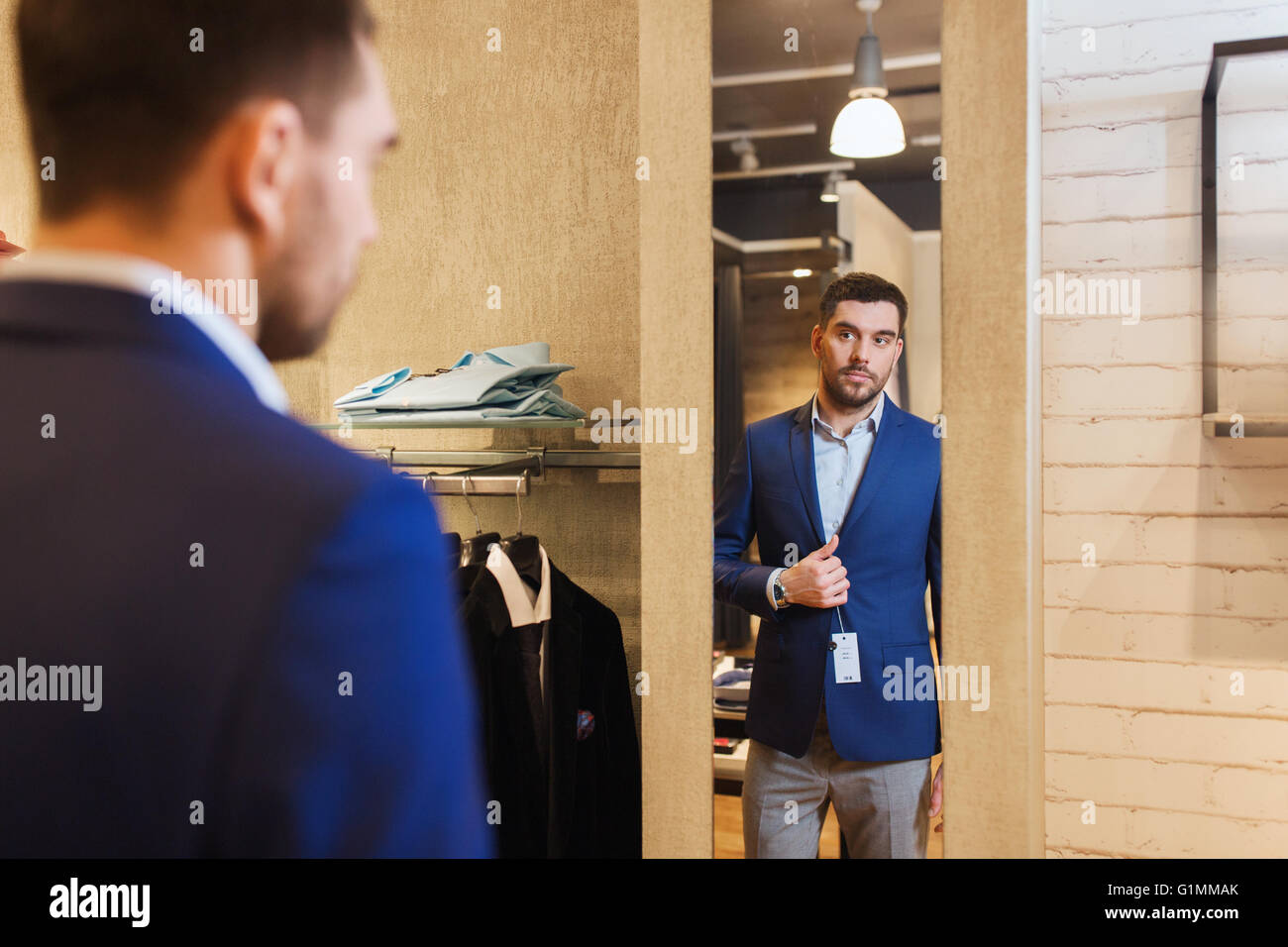 man trying jacket on at mirror in clothing store Stock Photo - Alamy