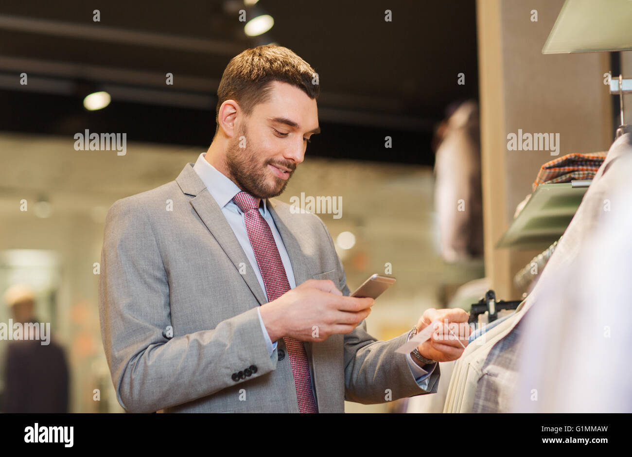 man in suit with smartphone at clothing store Stock Photo - Alamy