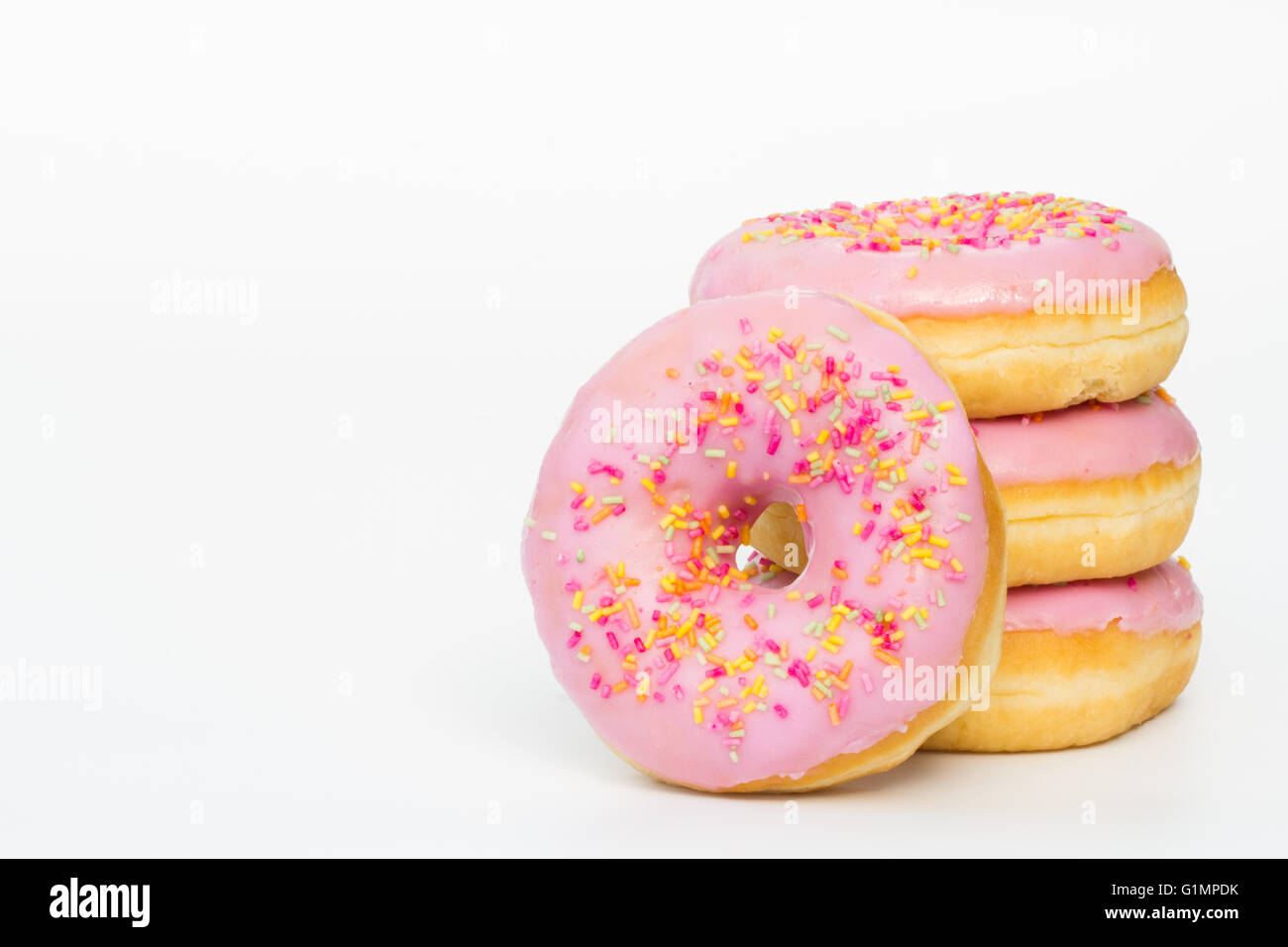 A stack of doughnuts with pink icing and sprinkles on an isolated white ...