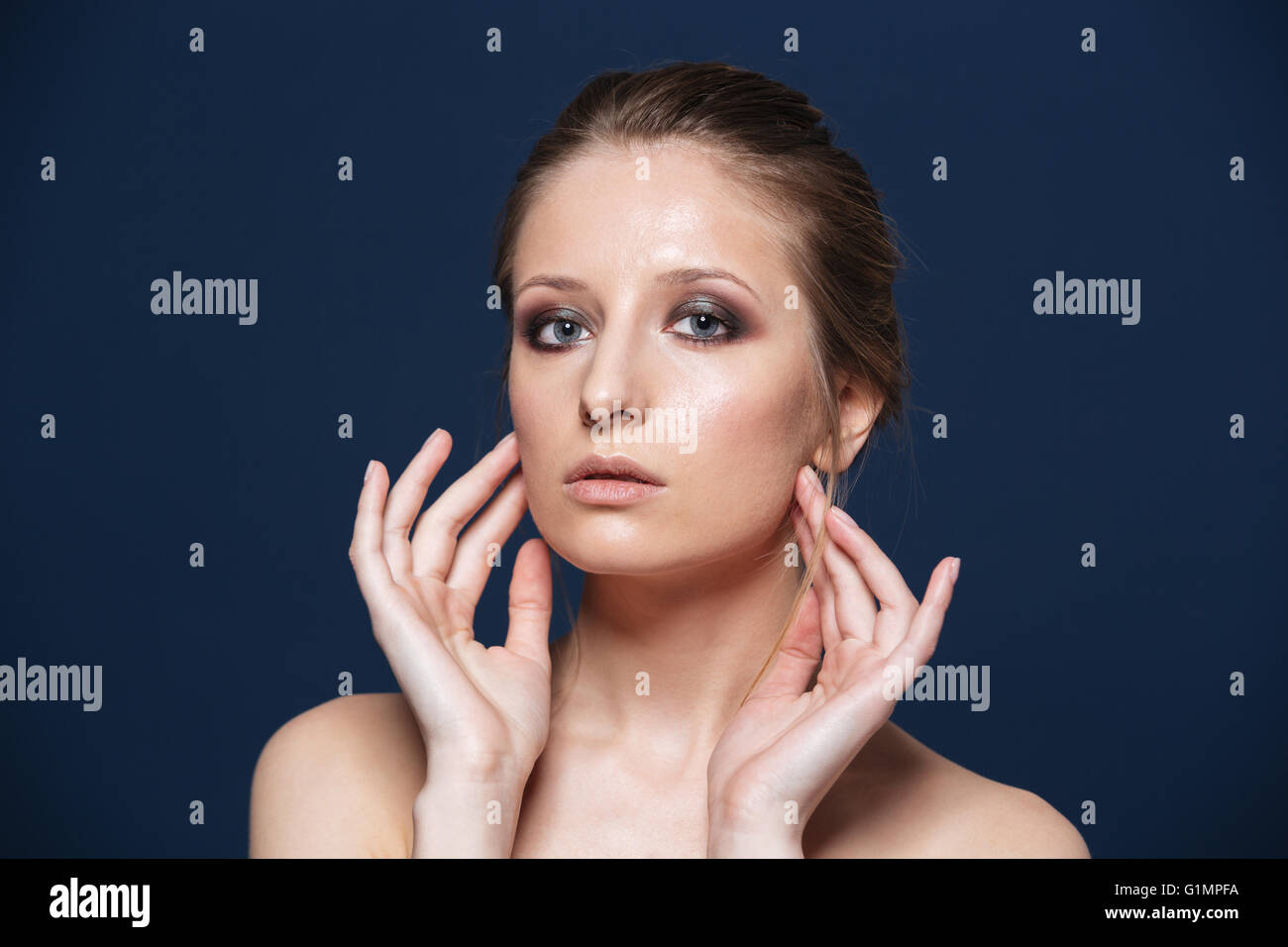 Beauty portrait of a charming woman with fresh skin standing over blue ...