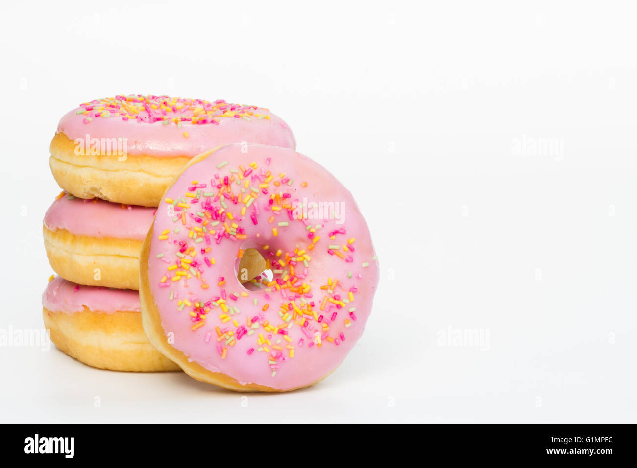 A stack of doughnuts with pink icing and sprinkles on an isolated white ...