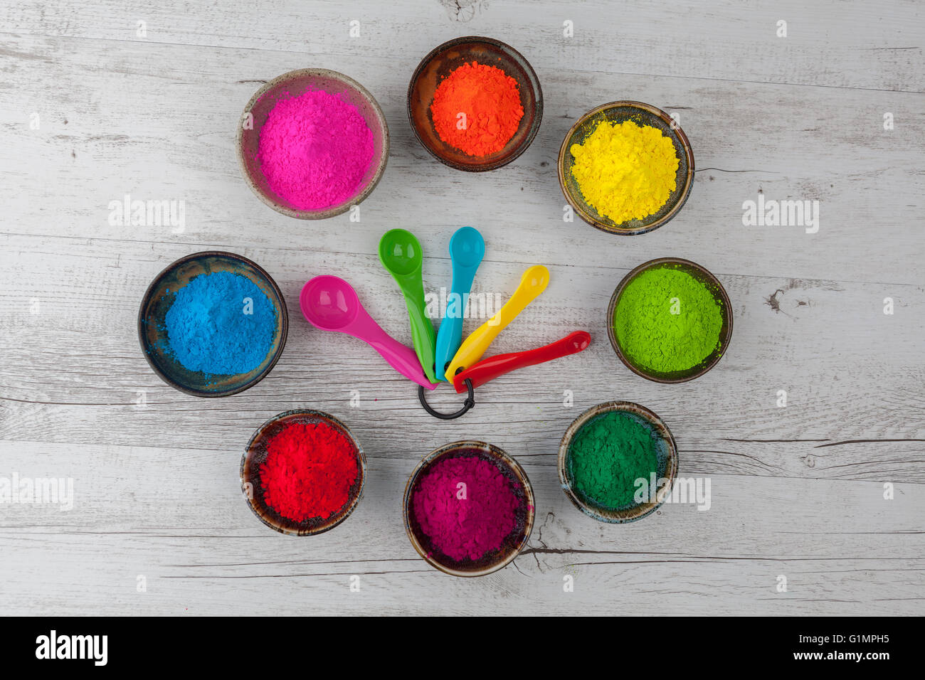 Vibrant colorful Holi powder in cups arranged in circle with measuring ...