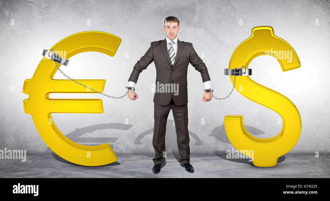 Man chained with golden dollar and euro signs Stock Photo - Alamy