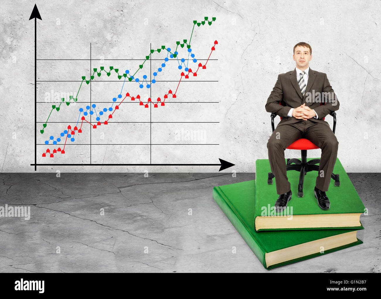 Businessman sitting on books with chart Stock Photo - Alamy