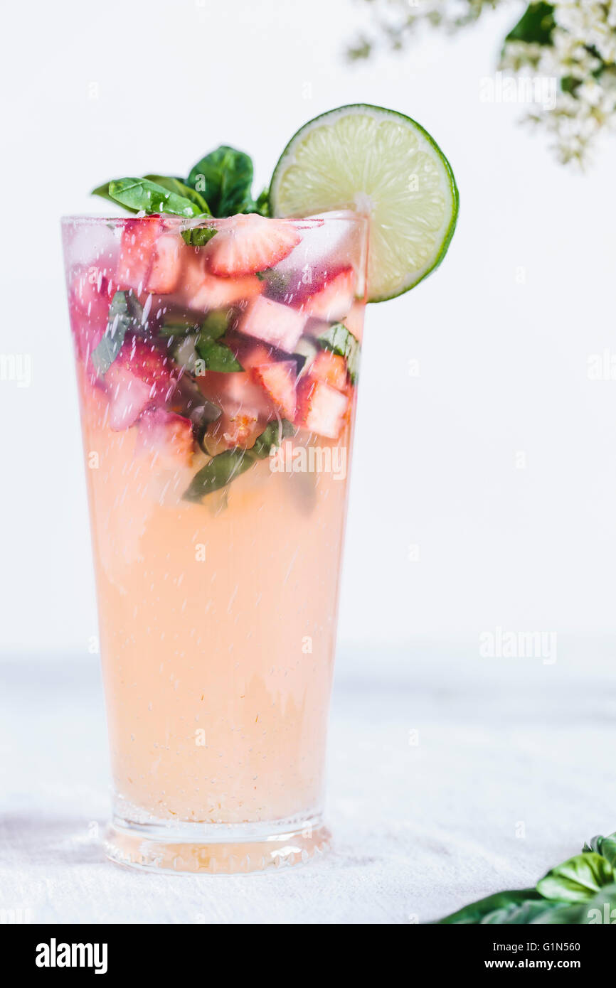 A glass full of Honey Sweetened Limeade with Strawberries and Basil is ...