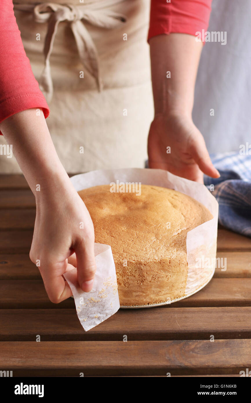 Female hands peeling the parchment paper from the sides of the sponge ...