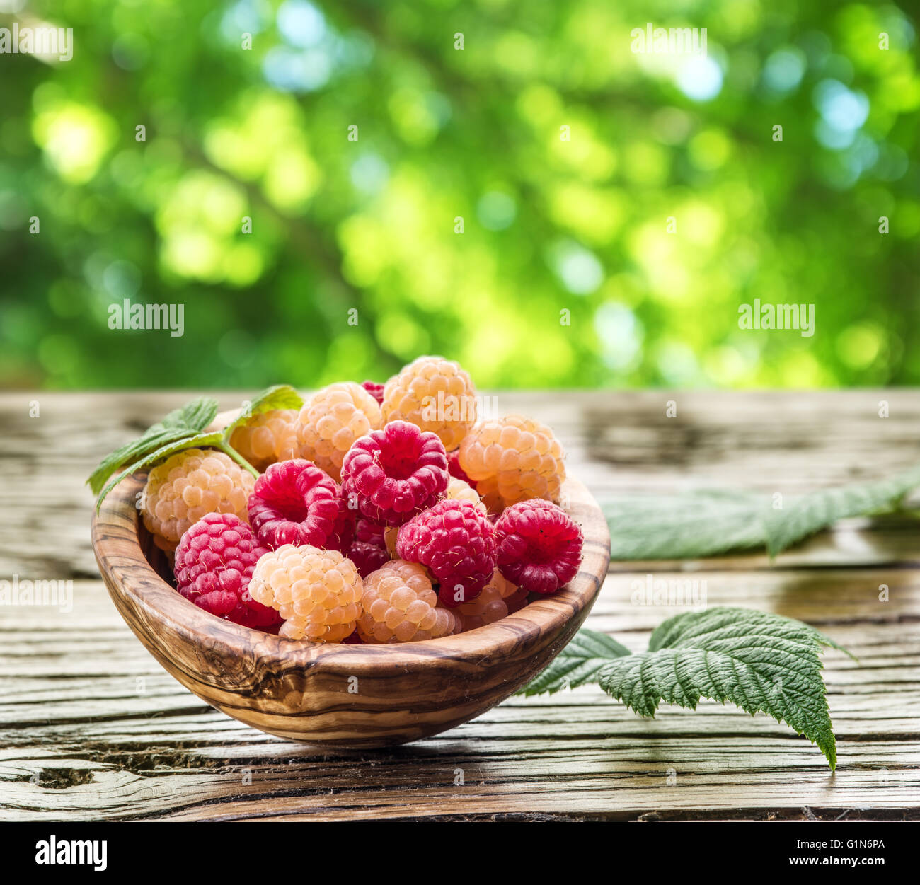 Raspberries in the wooden bowl on the table Stock Photo - Alamy