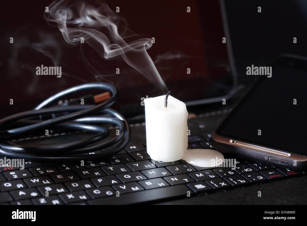 Blackout concept. Extinguished candle on laptop and smartphone Stock ...