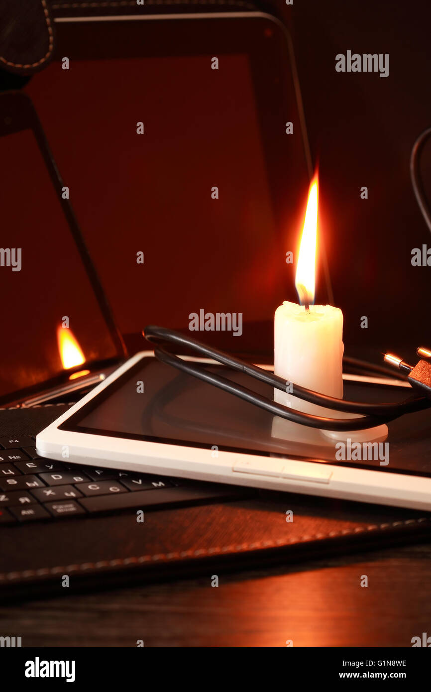 Blackout concept. Lighting candle on laptop and tablet Stock Photo - Alamy