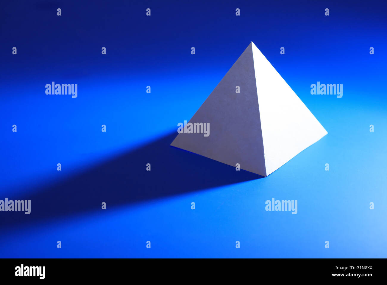 Geometry concept. One white paper pyramid on blue background Stock ...