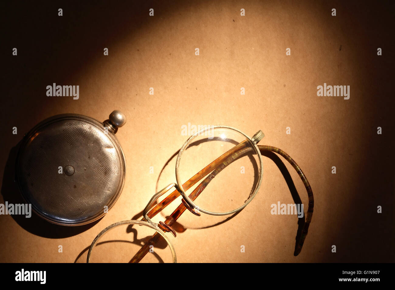 Old spectacles near closed pocket watch on brown paper background Stock ...
