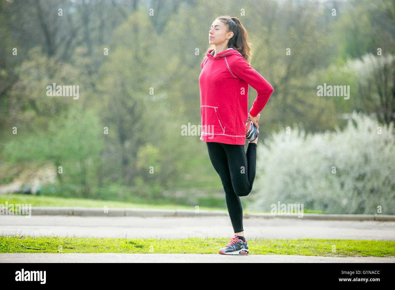 Portrait of sporty woman doing stretching exercises in park before ...