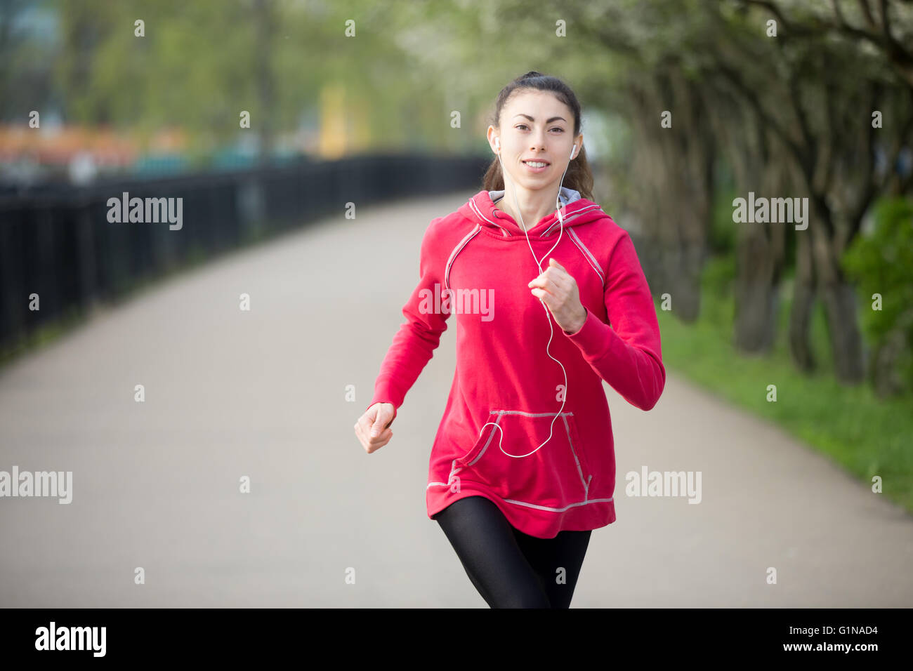 Portrait of smiling beautiful female running in park during everyday ...