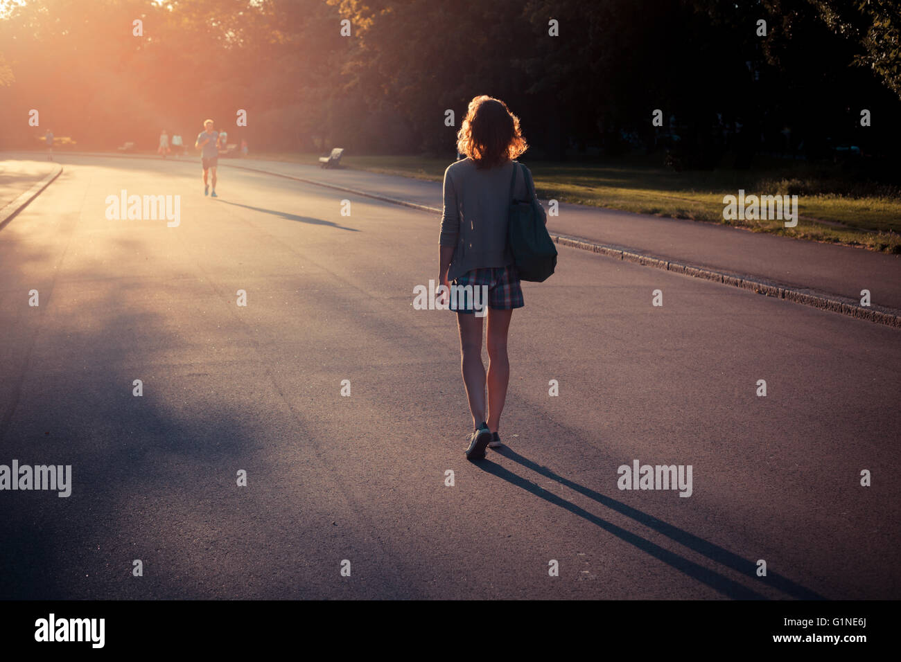 A young woman is walking into the sunset in a park Stock Photo - Alamy
