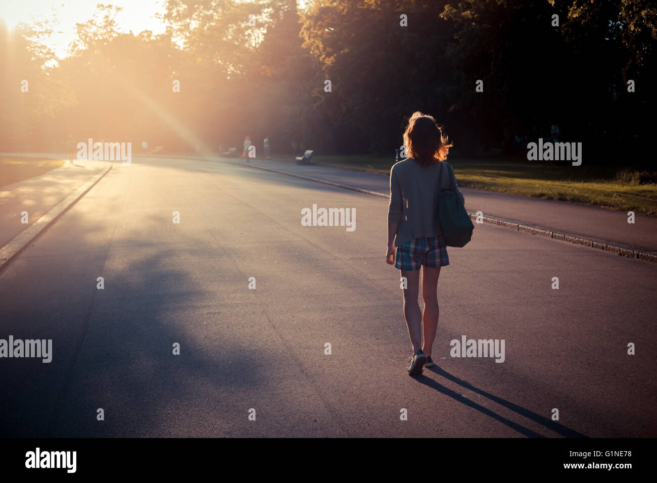 A young woman is walking into the sunset in a park Stock Photo - Alamy