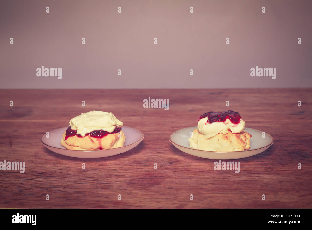 Two scones with cream and jam prepared both the Devon and Cornwall way ...