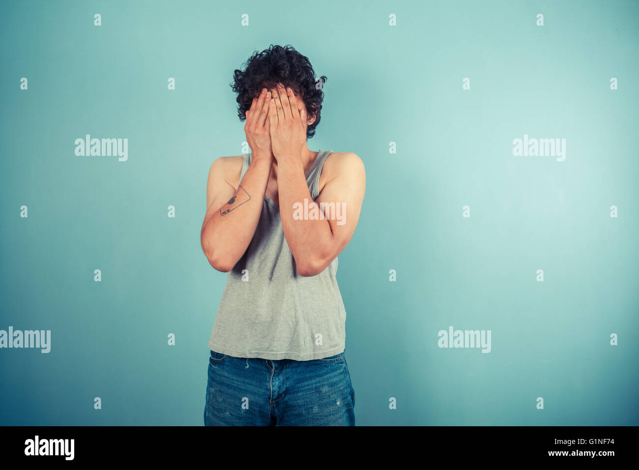 A young man is holding his face in his palms Stock Photo - Alamy
