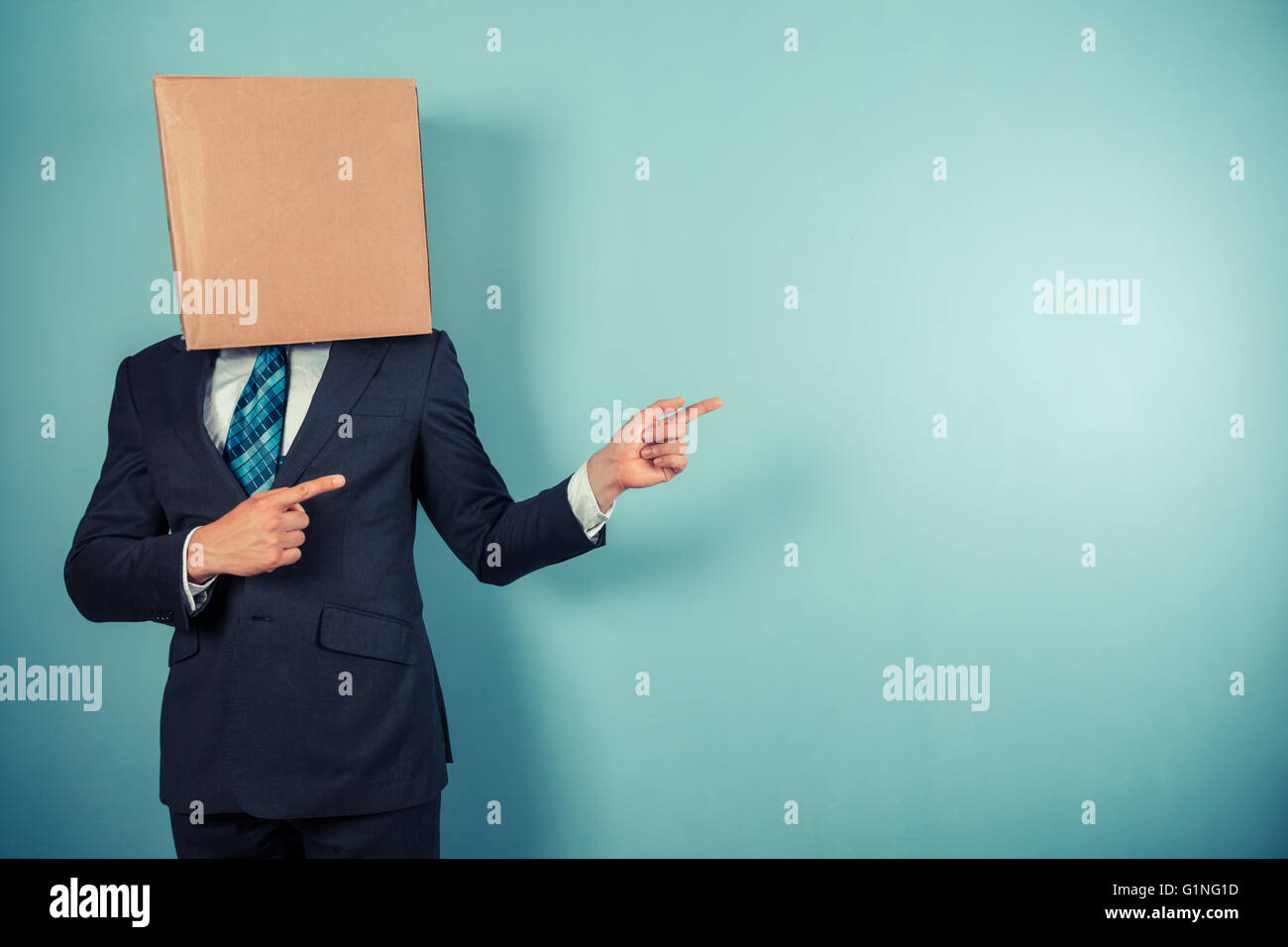 A businessman with a cardboard box on his head is pointing Stock Photo ...