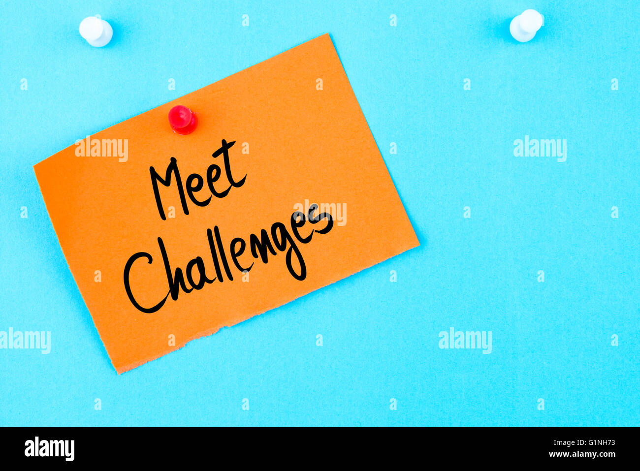 Meet Challenges written on orange paper note pinned on cork board with ...