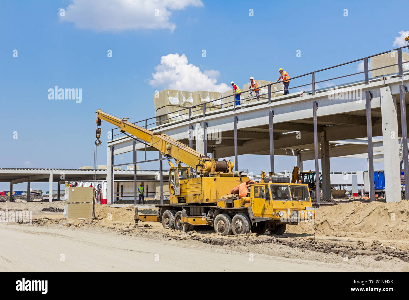 Mobile crane is loading cargo. View on construction site with machinery ...