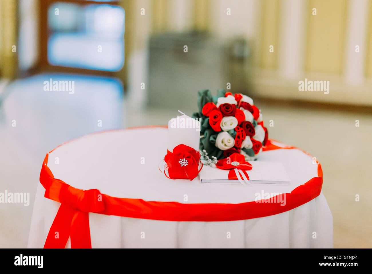 Wedding bouquet of white and red roses laying on a table with ribbon ...