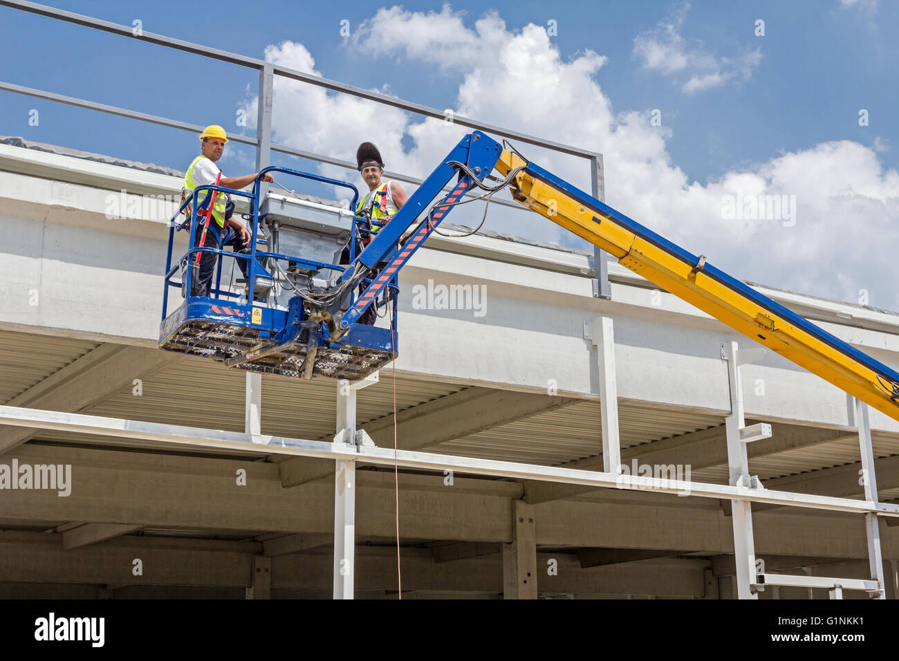 High elevated cherry picker with team of workers on construction site ...