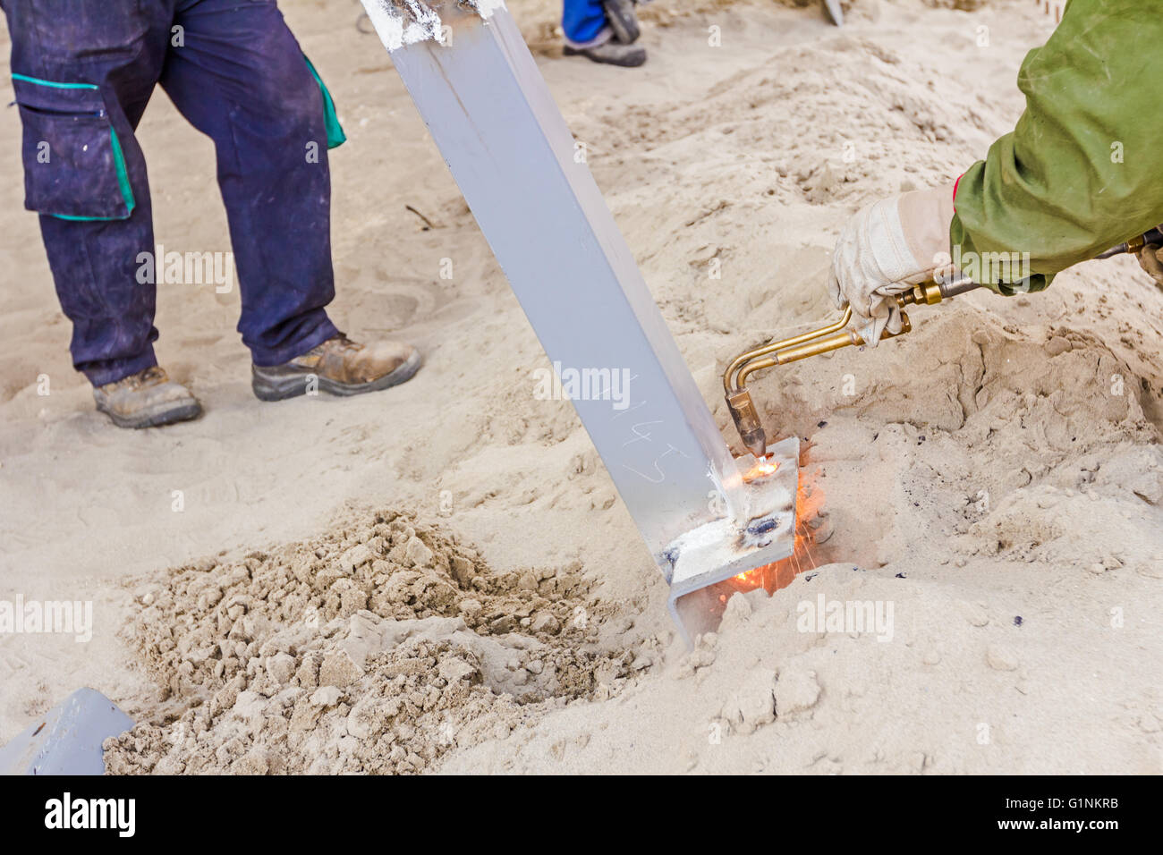 Metalworker is increasing holes diameter using metal torch. Worker is ...