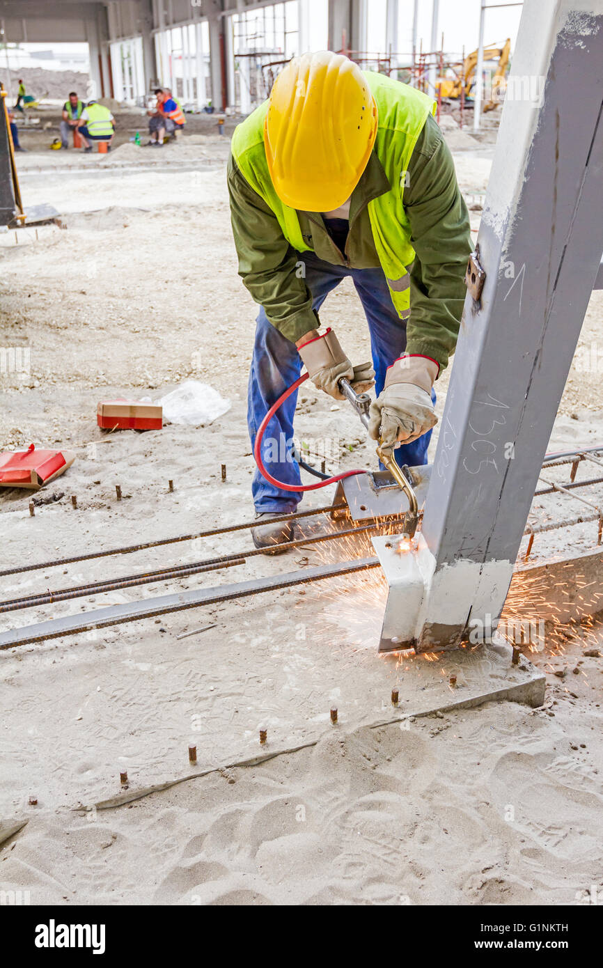 Metalworker is increasing holes diameter using metal torch. Worker is ...