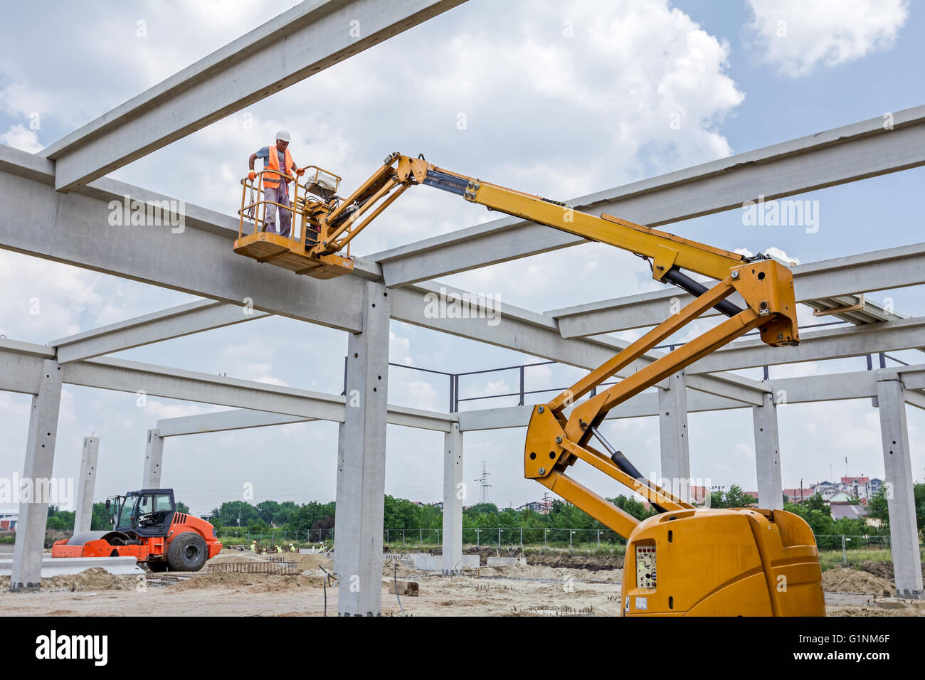 Worker is managing the orange cherry picker across building site Stock ...