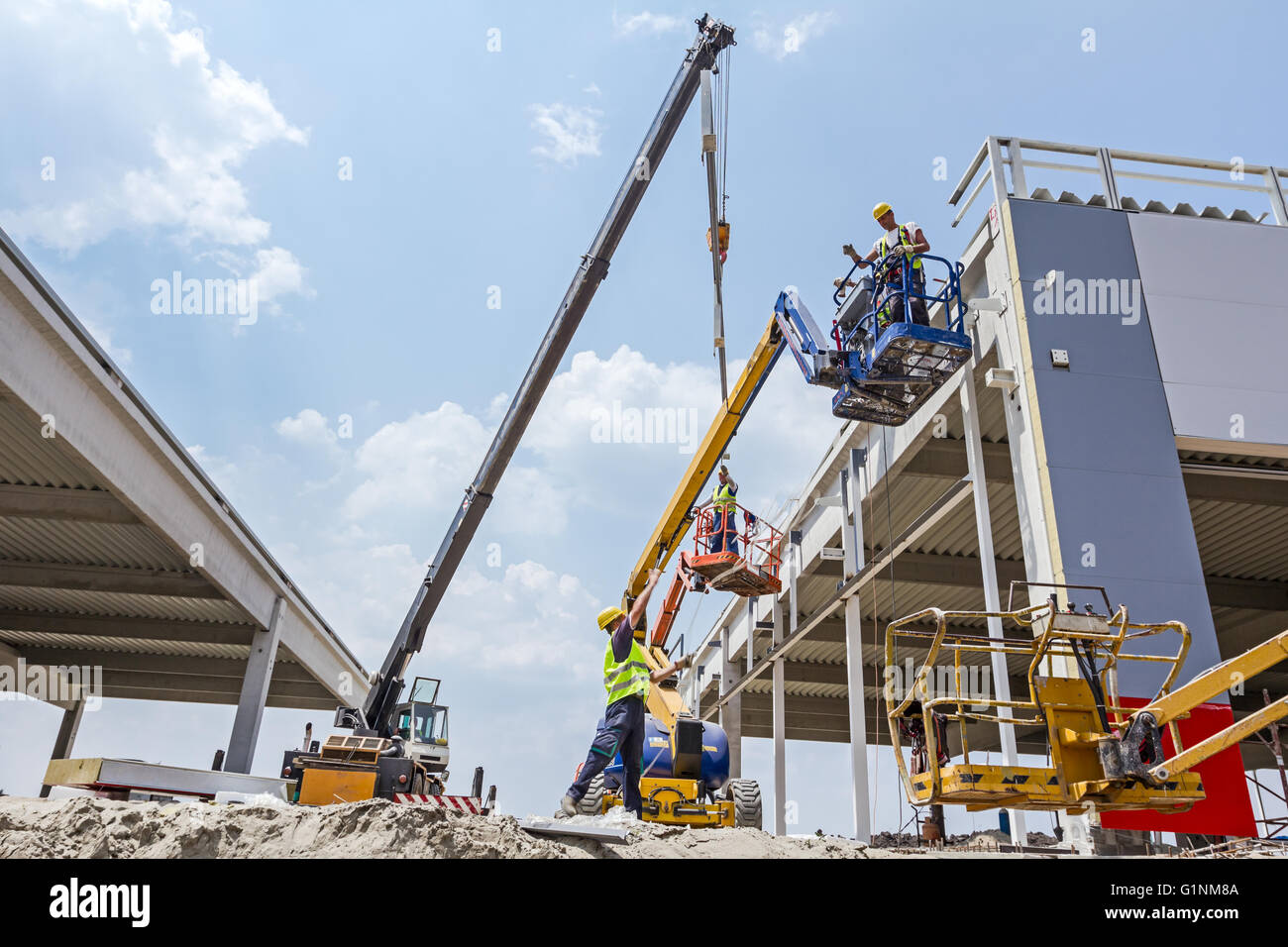 High elevated cherry picker with team of workers on construction site ...