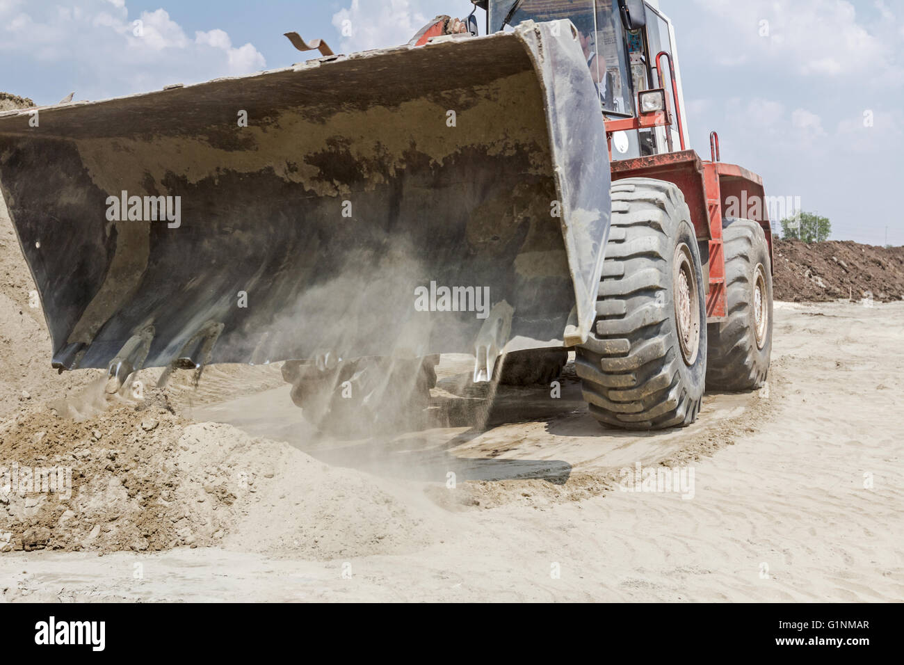 Red loader with wheels at earthmoving works. Bulldozer is pushing sand ...