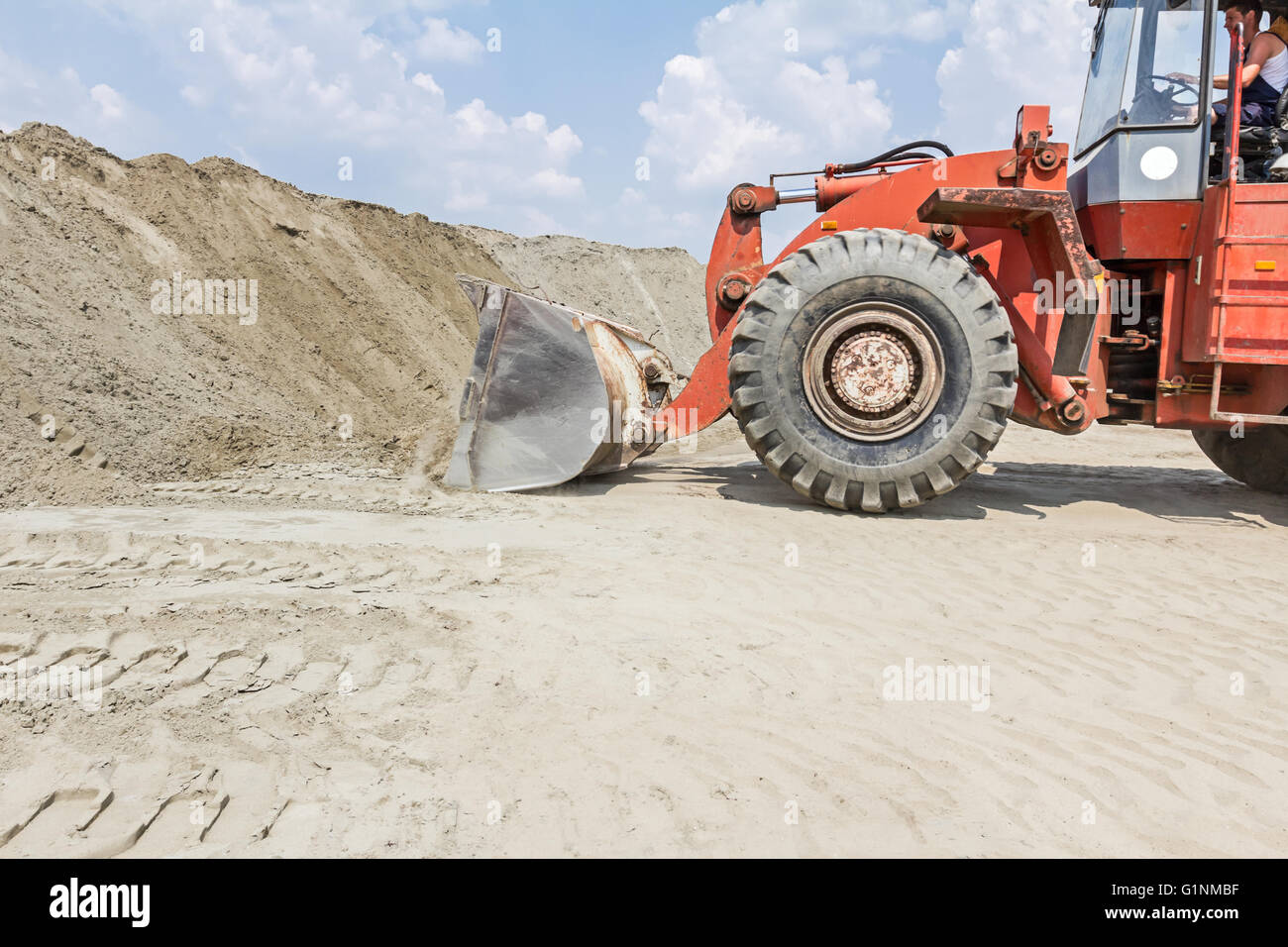 Red loader with wheels at earthmoving works. Bulldozer is pushing sand ...