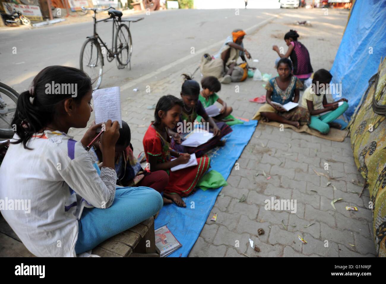 Allahabad, India. 17th May, 2016. Child of slum area reading at a road ...