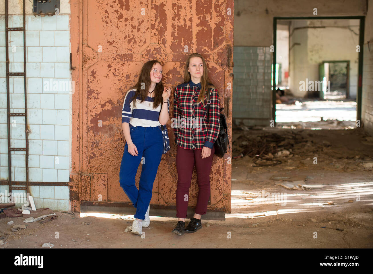 Two teen girls standing at the iron door in an abandoned building Stock ...