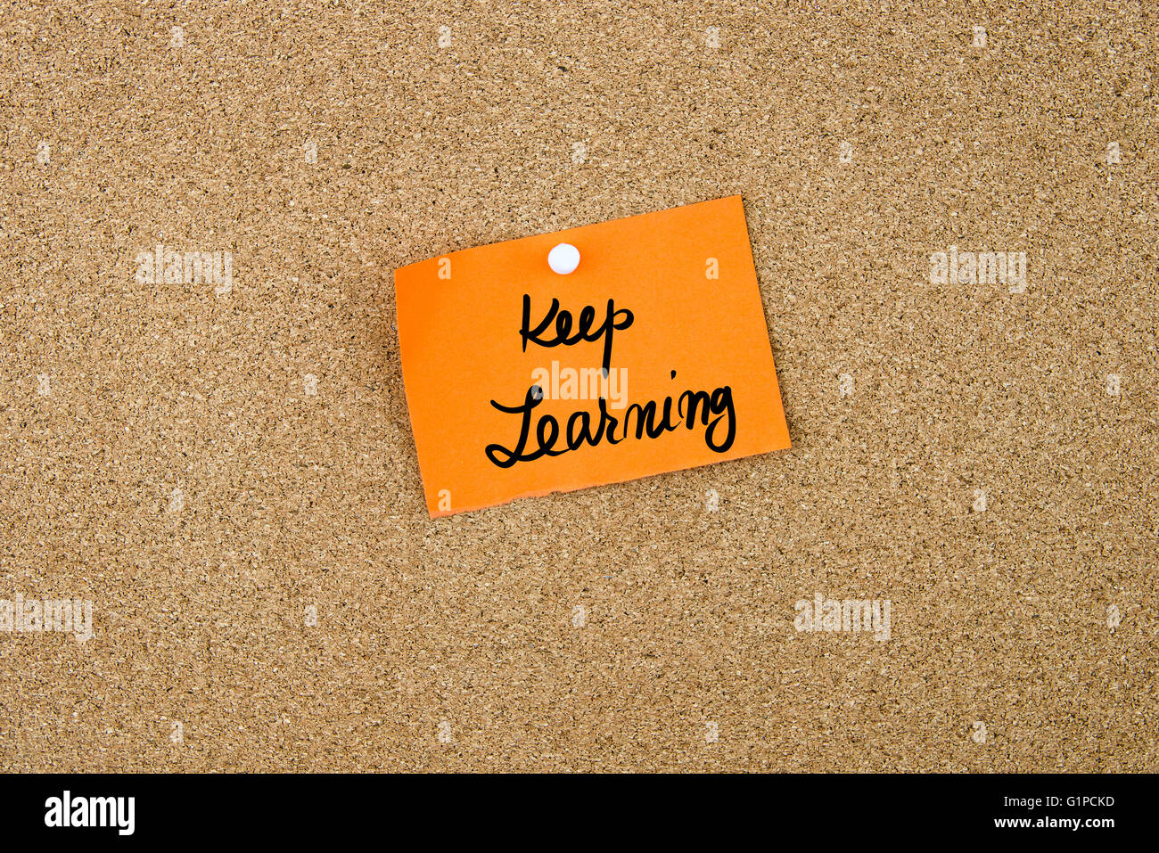 Keep Learning written on orange paper note pinned on cork board with ...