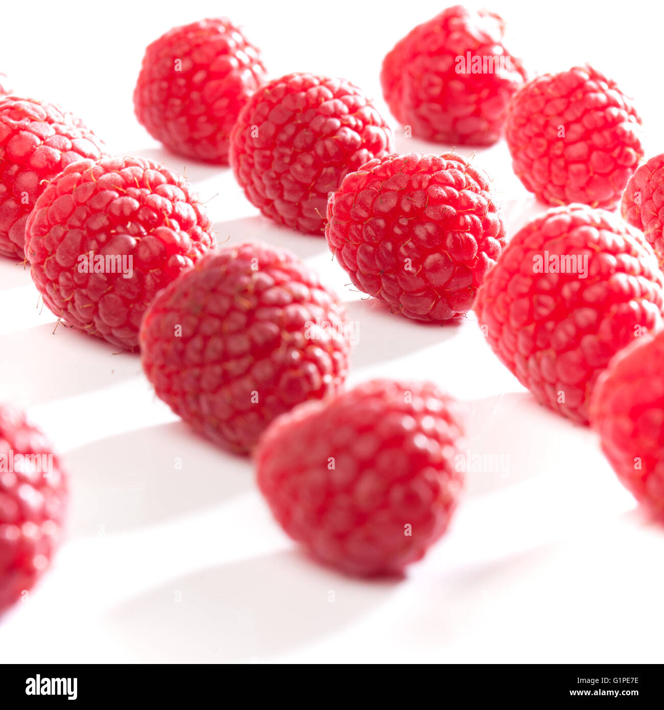 Closeup to fresh red raspberries lined up, isolated on white background ...