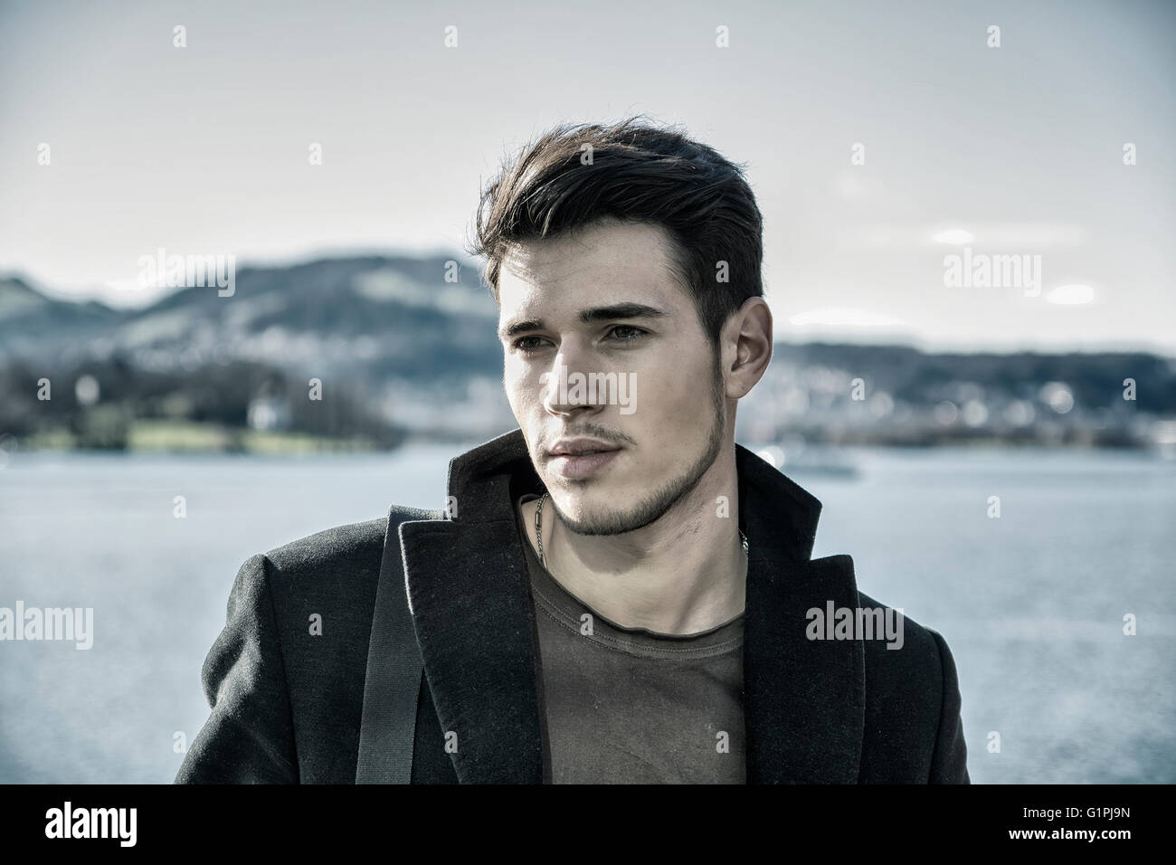 Handsome young man on Luzern lake's shore in a sunny, peaceful day ...