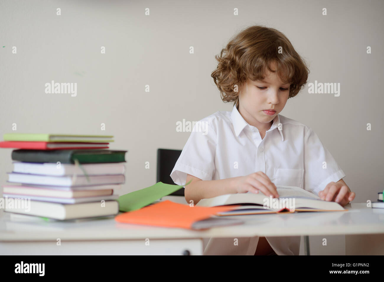 Schoolboy sitting at the desk and reading a book Stock Photo - Alamy